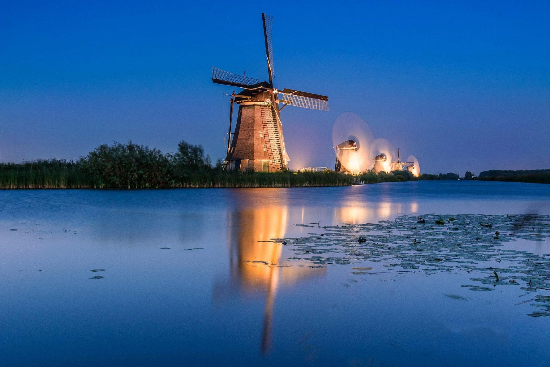 Serene Night Reflections: Windmills by the River HD Wallpaper