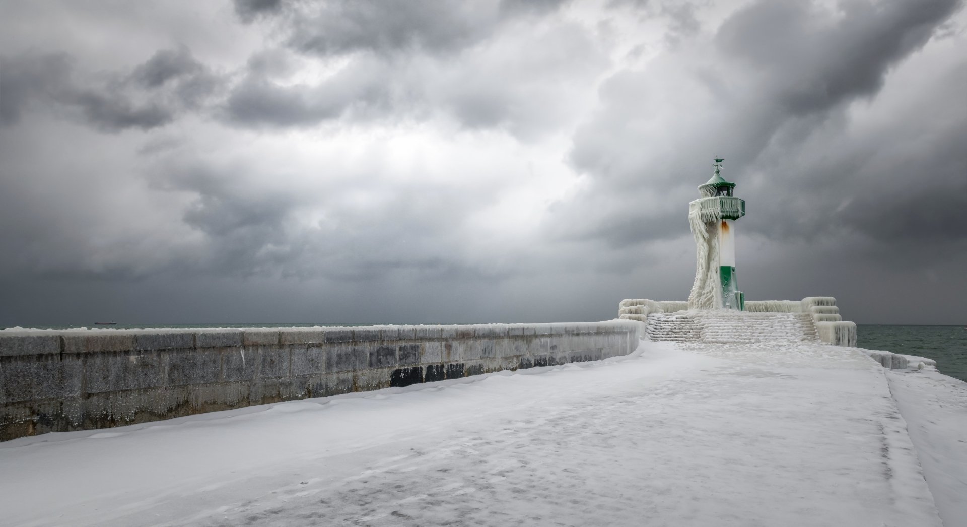 Winter’s Icebound Lighthouse Under Moody Clouds – HD Wallpaper